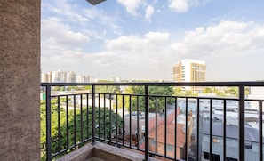 Uma varanda com vista para edifícios e vegetação ao redor.