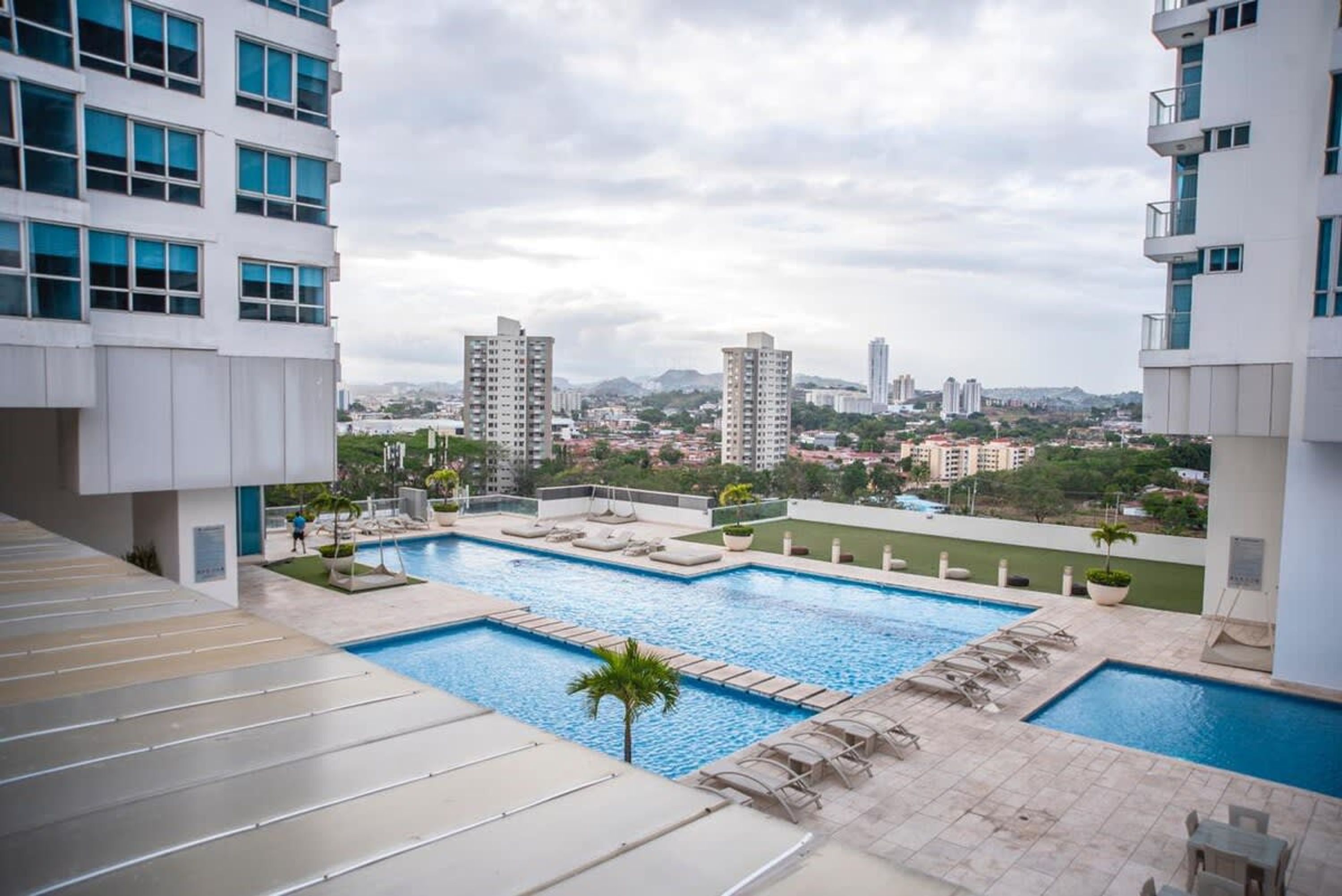 Piscina no terraço com espreguiçadeiras e vista para a cidade.