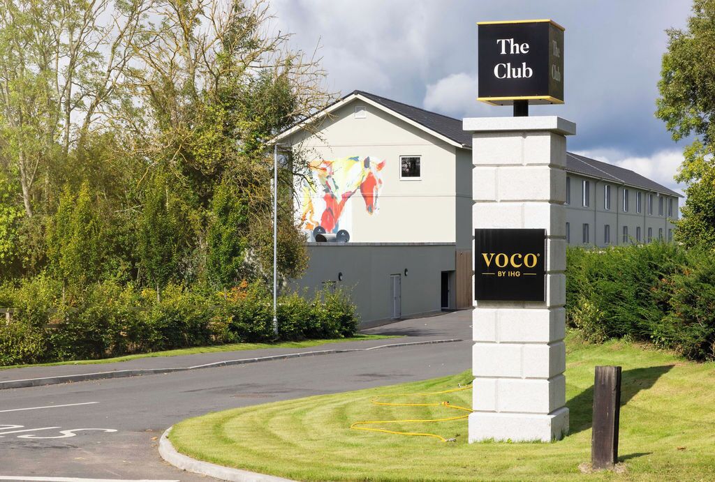 Um edifício com uma placa que diz "The Club" e "VOCO BY IHG".
