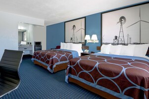 Quarto de hotel com duas camas, uma escrivaninha, uma cadeira e uma janela grande com vista para um moinho.