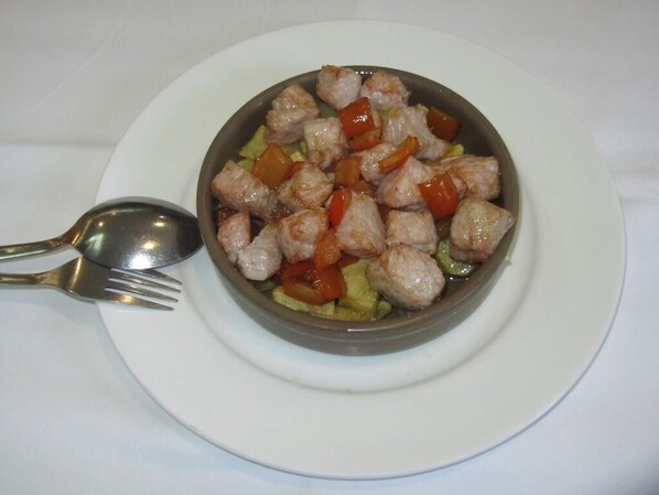 Uma tigela de comida com uma colher sobre um prato branco.
