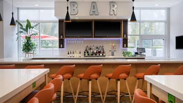 Uma área de bar com balcão, banquetas, uma televisão e um letreiro que diz 'BAR'.