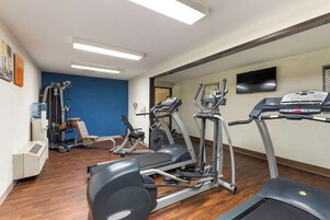Uma academia com equipamentos de cardio, máquinas de musculação e um bebedouro.