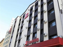 Edifício de hotel com vários aparelhos de ar condicionado, uma placa vermelha com caracteres chineses e toldo vermelho.