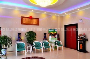 Um hall com cadeiras estofadas em verde, uma porta vermelha e um painel decorativo na parede.