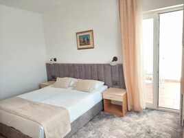 Quarto com cama, mesas de cabeceira, um quadro e uma porta de vidro deslizante.