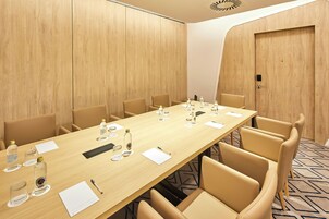 Sala de conferência com uma mesa comprida, cadeiras, garrafas de água, copos e cartões de identificação.