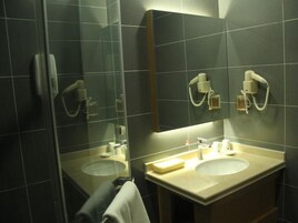 Um banheiro moderno com um espelho grande, duas pias e um porta-toalhas.
