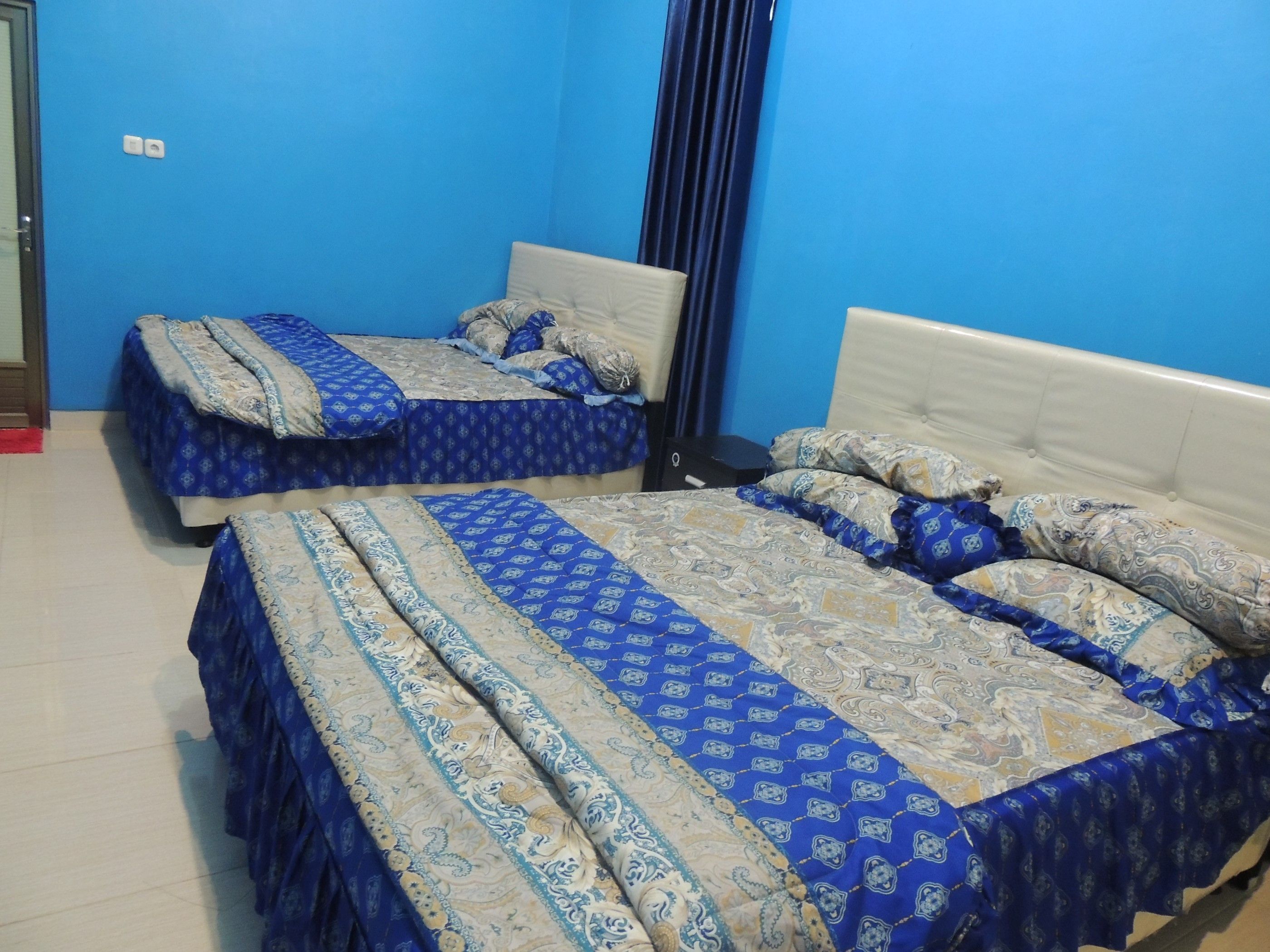 Duas camas de solteiro com cabeceiras, uma parede azul e um teto branco.