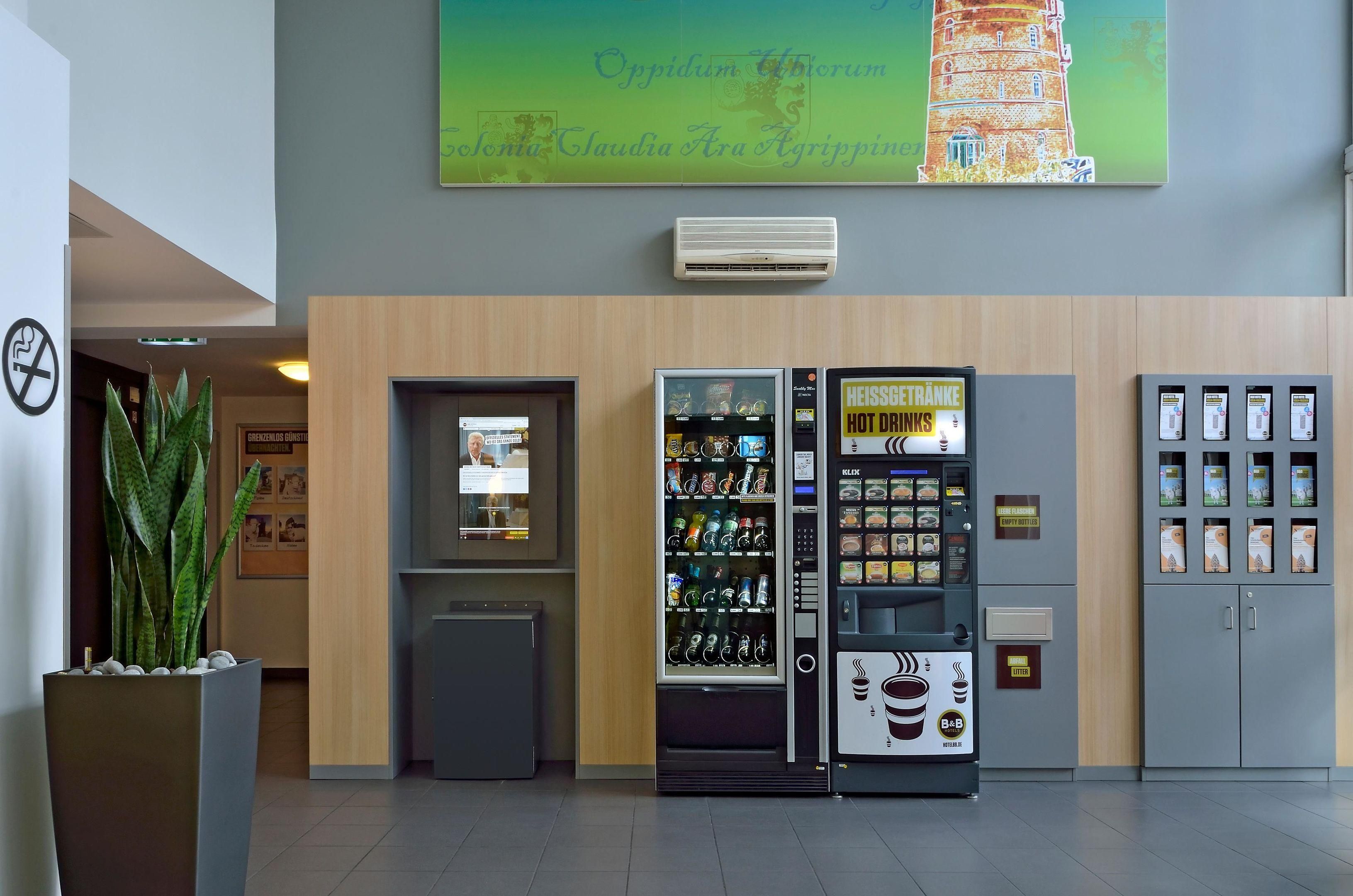 Um saguão de hotel com uma máquina de venda automática, um frigorífico e uma máquina de café.