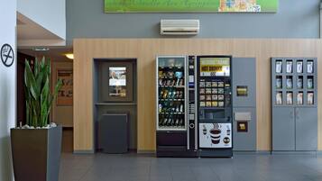 Um saguão de hotel com uma máquina de venda automática, um frigorífico e uma máquina de café.