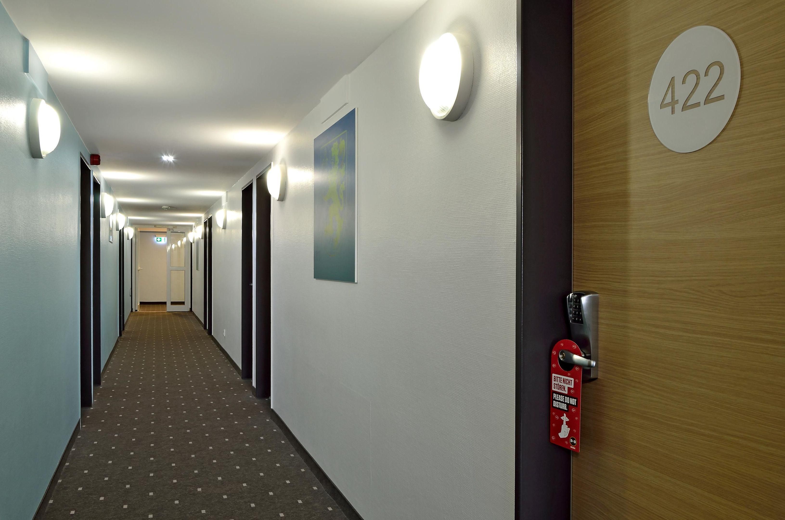 Corredor de hotel com placa de número 422, alarme de incêndio e porta com fechadura eletrônica.