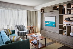 Uma sala de estar moderna com sofá, poltrona, mesa de centro e um quadro na parede.
