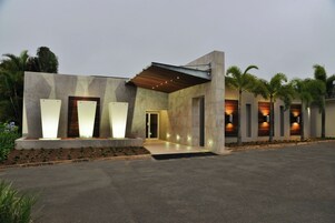 Um edifício moderno com fachada de concreto, grandes janelas e entrada coberta.