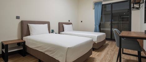 Quarto de hotel com duas camas, uma escrivaninha e uma cadeira.