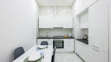 Cozinha moderna com armários brancos, fogão e mesa de jantar posta para dois.