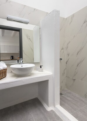 Uma casa de banho com uma pia branca, espelho, chuveiro e paredes com padrão marmorizado.