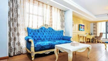 Quarto com sofá azul, mesa branca e parede amarela.