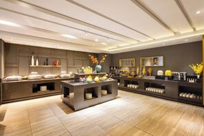 Um hall de hotel moderno, com uma recepção central, área de estar e elementos decorativos.