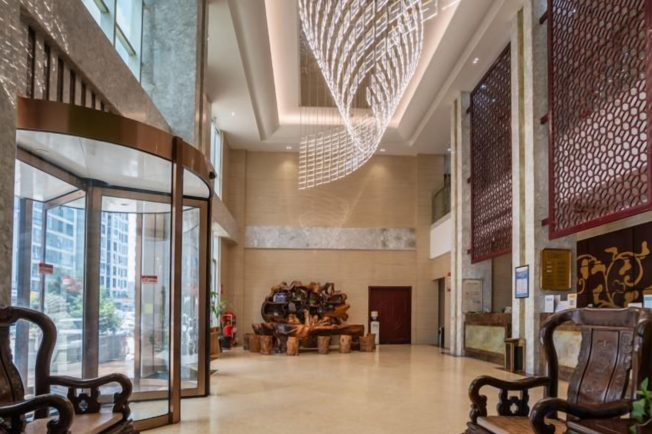 Um hall amplo com um lustre moderno, um balcão de recepção e mobiliário de madeira tradicional.
