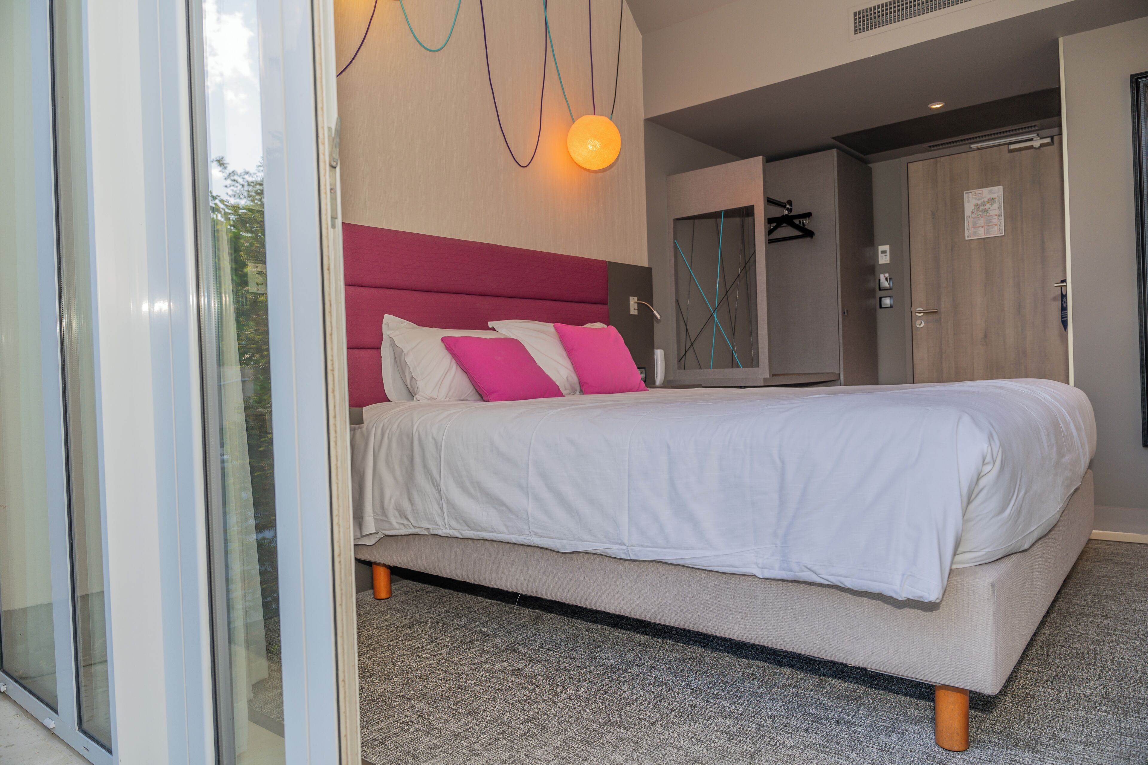Quarto moderno com cama grande, porta de correr de vidro e guarda-roupa de madeira.