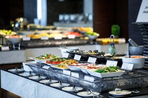 Buffet com diversas estações de comida, cada qual identificada por um nome.