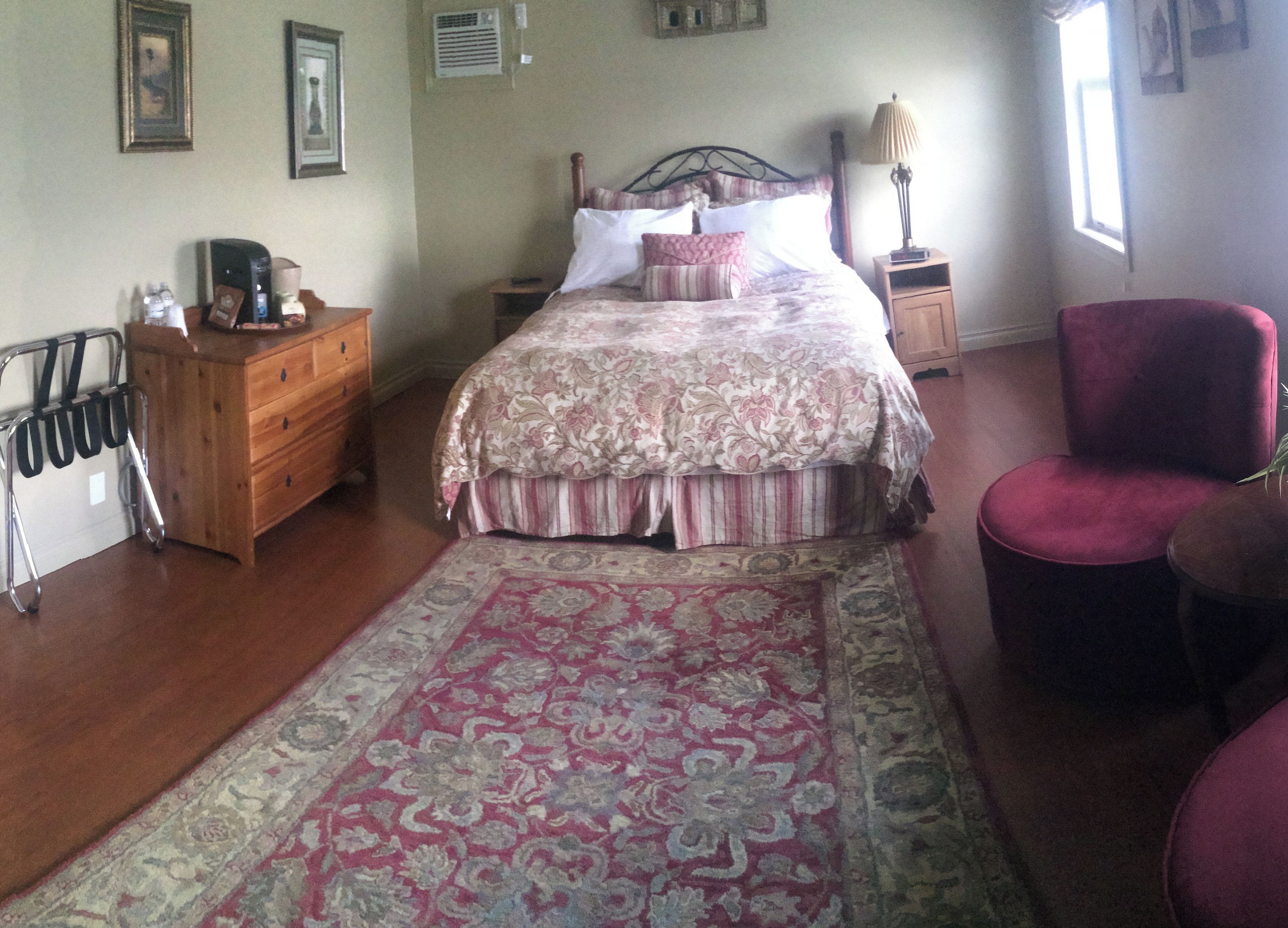 Quarto com cama, cômoda, cadeira e tapete.