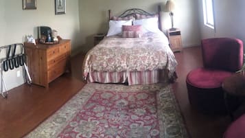 Quarto com cama, cômoda, cadeira e tapete.