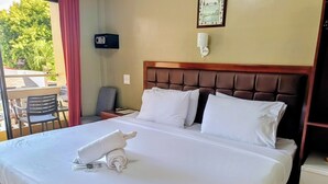 Quarto de hotel com uma cama grande, cabeceira de madeira e vista para o exterior.