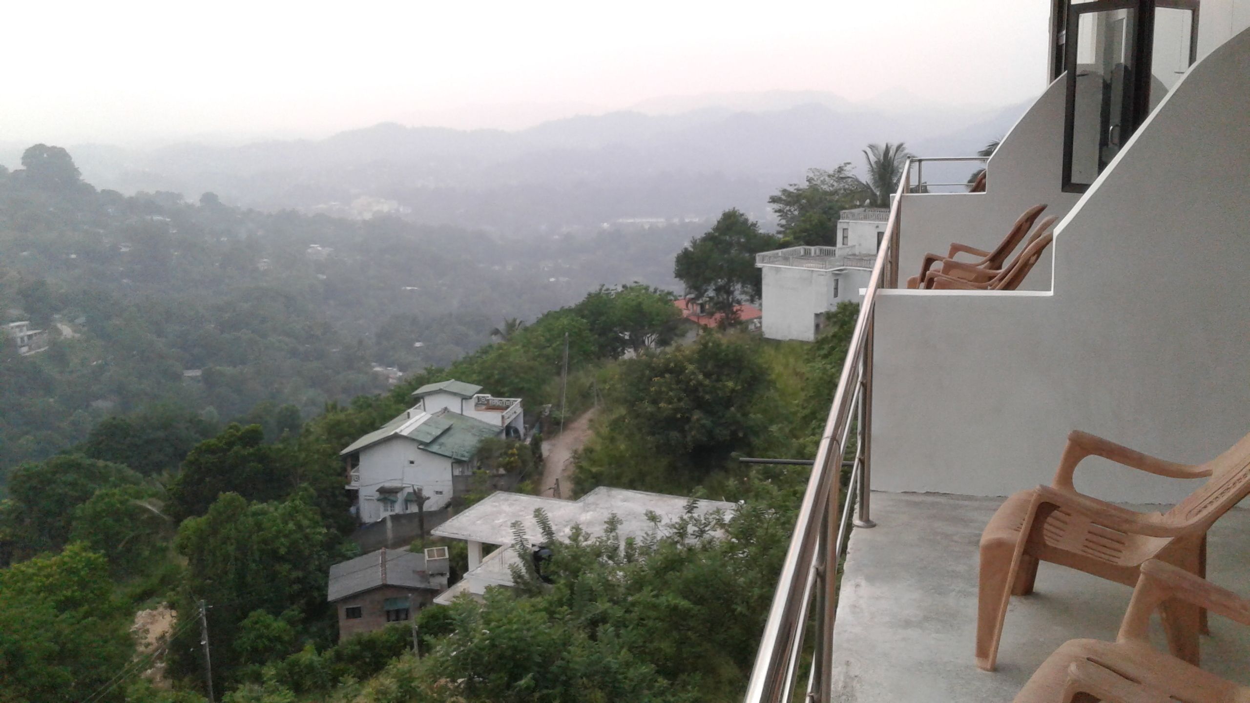 Uma varanda com vista para um vale e montanhas ao longe.