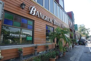 Um edifício com fachada de madeira e uma placa com a inscrição "Bangkok Travel Hotel".