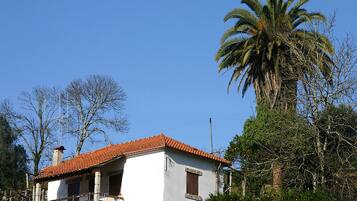 Um edifício de dois andares com telhado de telhas vermelhas, uma varanda e fachada branca.
