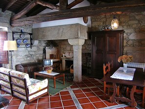 Um quarto rústico com paredes de pedra, lareira, mesa de madeira e televisão.