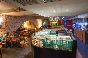 Restaurante com parede de pedra, móveis de madeira e um balcão de frutos do mar.