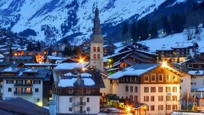 Uma cidade coberta de neve com edifícios tradicionais e uma torre de igreja imponente.