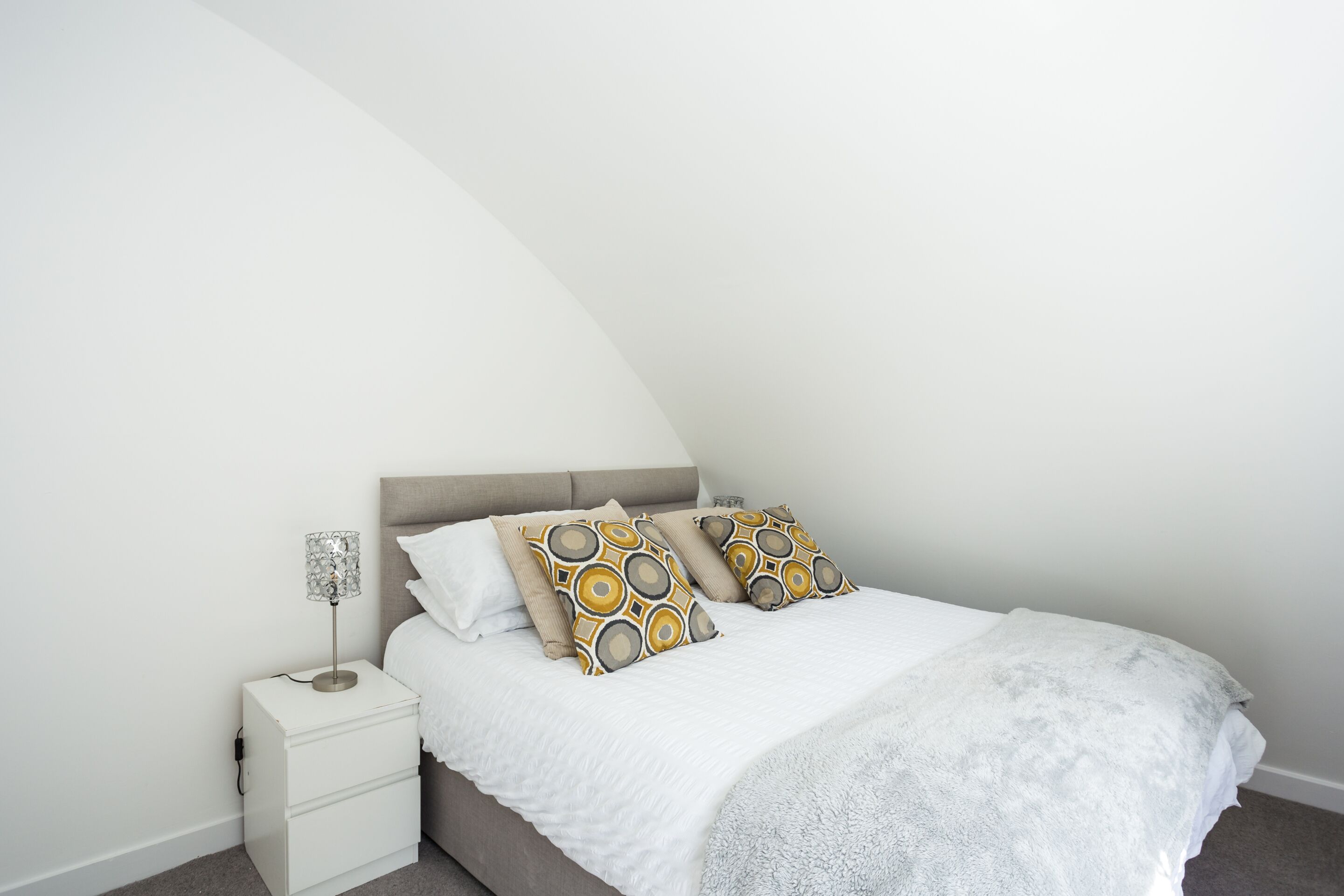 Quarto com uma cama, duas mesas de cabeceira e um criado-mudo.