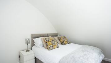 Quarto com uma cama, duas mesas de cabeceira e um criado-mudo.