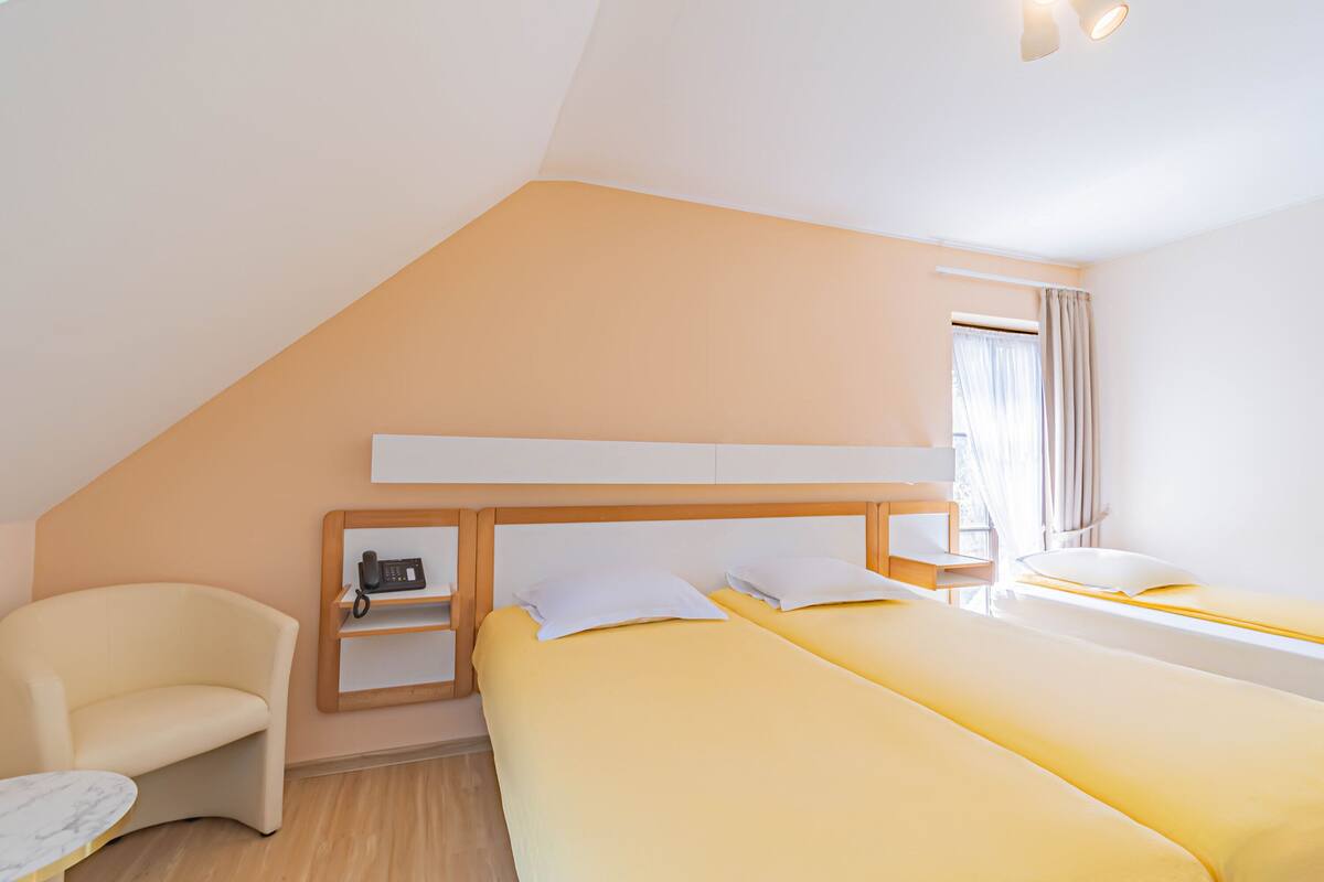 Quarto de hotel com duas camas, um sofá, uma mesinha e um telefone em uma prateleira.