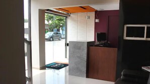 Uma área de recepção com uma mesa de madeira, uma televisão e uma porta que dá para o exterior.