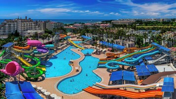 Um parque aquático com várias piscinas e toboáguas, cercado por edifícios e um céu claro.
