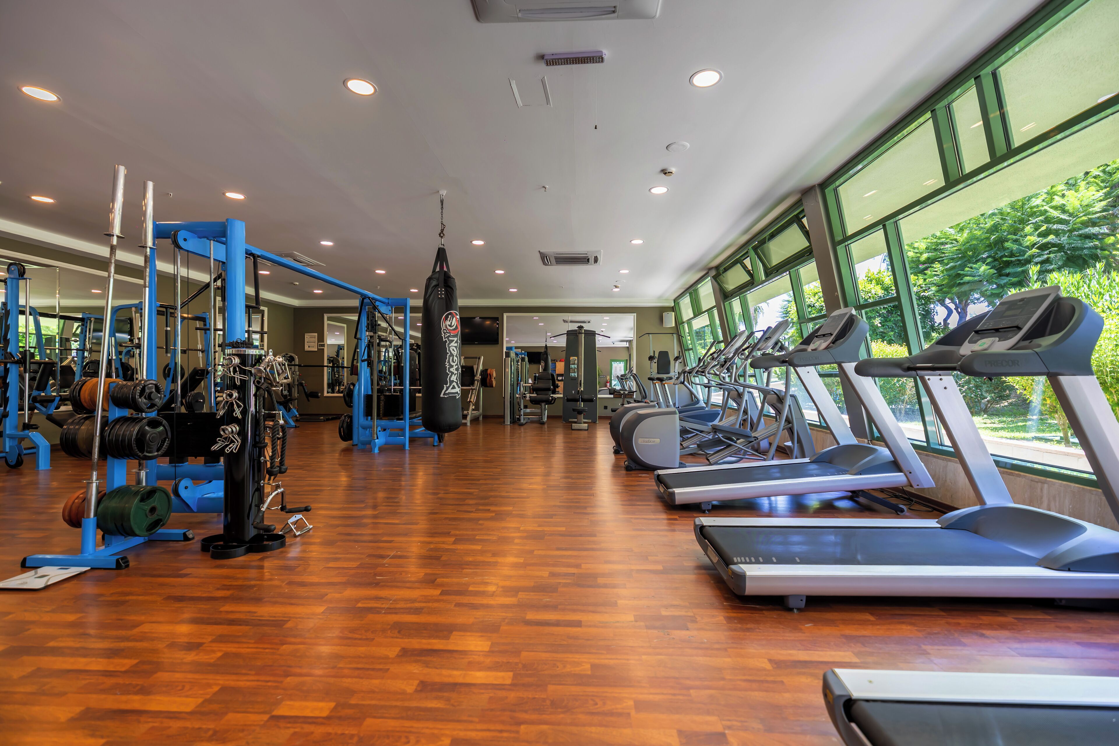 Academia com esteiras, aparelhos de musculação e saco de pancada.