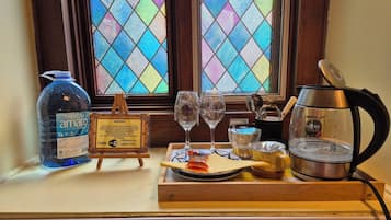 Um minibar com uma garrafa de água, copos de vinho, uma cafeteira e um tabuleiro.