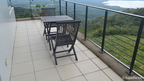 Varanda com mesa e cadeiras, oferecendo vista para um lago e vegetação ao redor.
