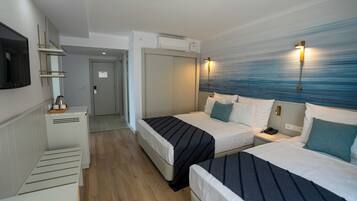 Quarto de hotel com duas camas, televisão, frigobar e banheiro.