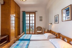 Quarto com duas camas, guarda-roupa de madeira e janela com cortinas.
