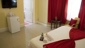 Quarto de hotel com uma cama, televisão, mesinha, cadeira e escrivaninha.