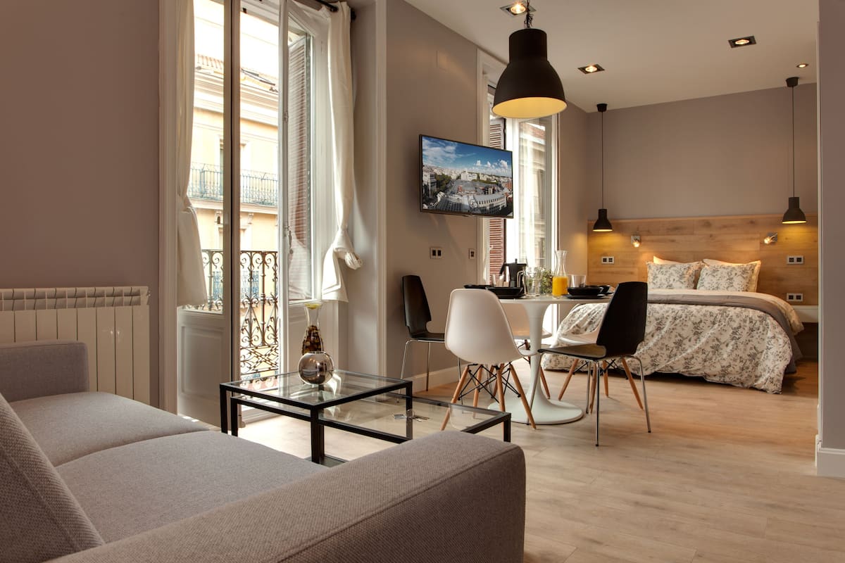 Quarto de hotel moderno com cama, área de jantar e sala de estar.