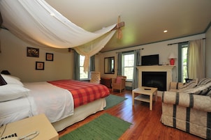 Quarto com cama, sofá, lareira e televisão.