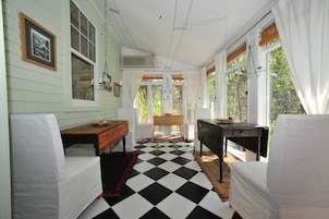 Um quarto com chão xadrez, paredes brancas e uma mesa de madeira.