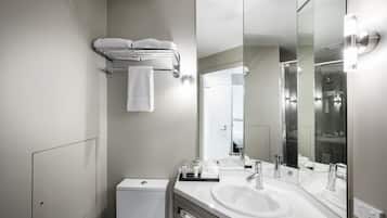 Uma casa de banho moderna com um espelho grande, lavatório branco e porta-toalhas.
